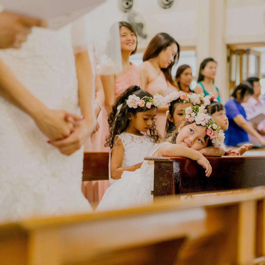 Wedding Ceremony Moment: Flower-Crowned Girls Resting at a Church Pew in Soft, Warm Light