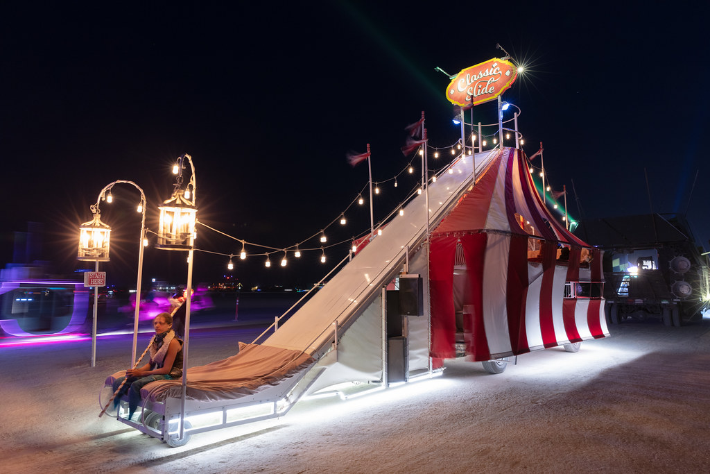 Classic Slide at Burning Man: Striped Carnival Structure Illuminated by String Lights at Night