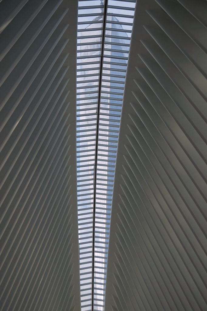 Interior skylight atrium at Westfield World Trade Center, New York, with a distant glass tower framed by the roof window