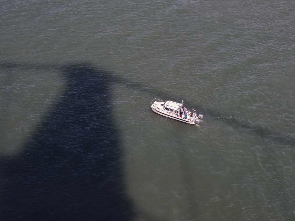 Aerial View: Shadow of a Suspension Bridge Over the Bay, with a Small Motorboat