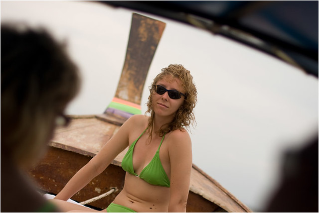 Portrait on a boat deck: woman in lime-green bikini with sunglasses, captured with shallow depth of field