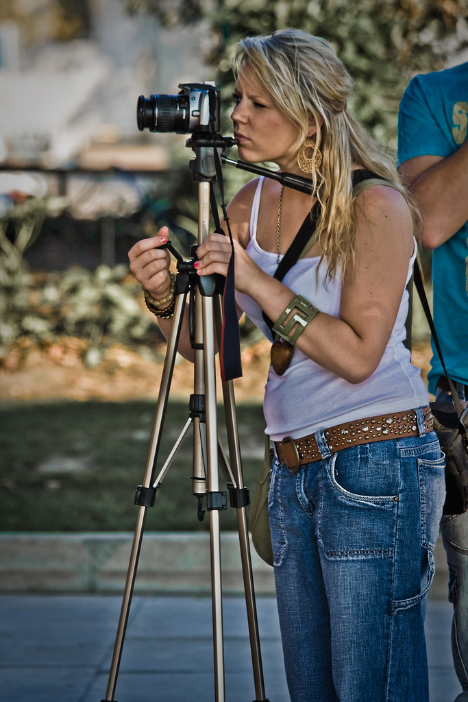Blonde Camerawoman Adjusting a Canon Telephoto Setup on a Tripod During Outdoor Shoot