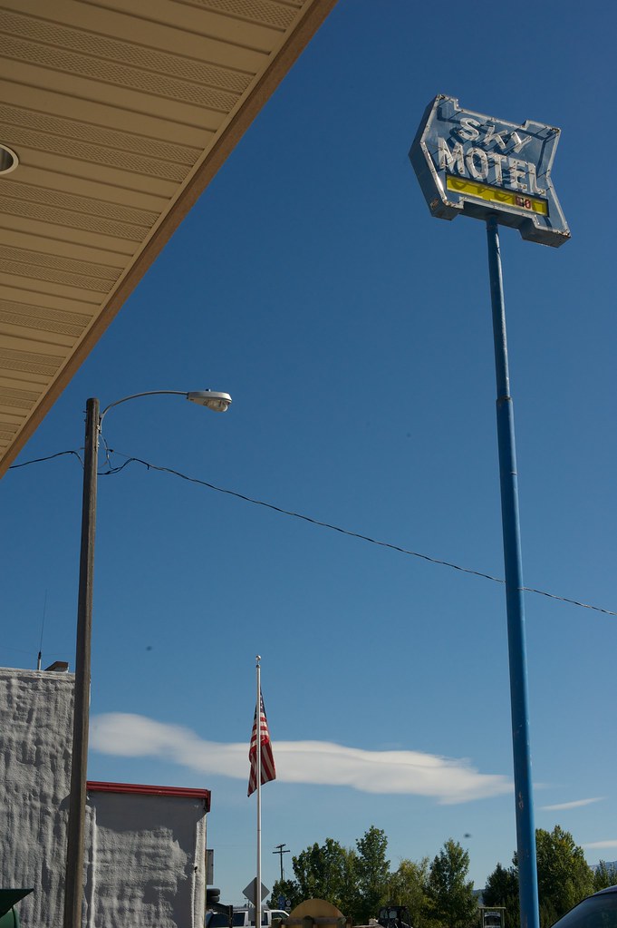 Sky Motel sign on a clear blue day, roadside scene with flagpole, streetlamp, and overhanging canopy