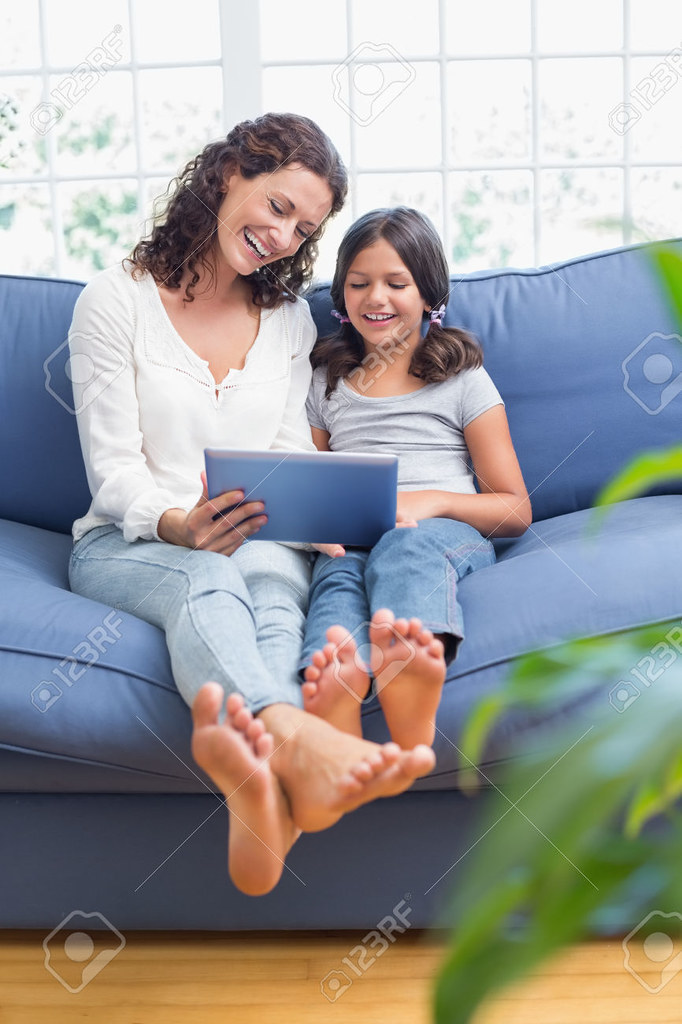 Happy mother and daughter sitting on the couch and using t… | Flickr