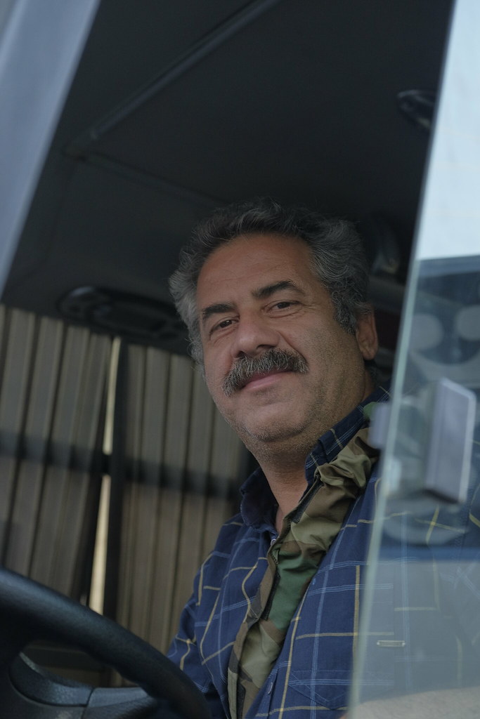 Portrait inside a truck cab in Iran: middle-aged driver with blue plaid shirt