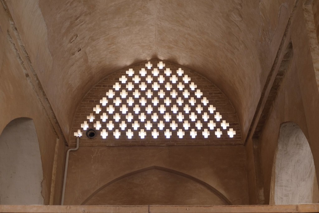 Sunlight through a semicircular perforated brick lattice in a vaulted Iranian chamber
