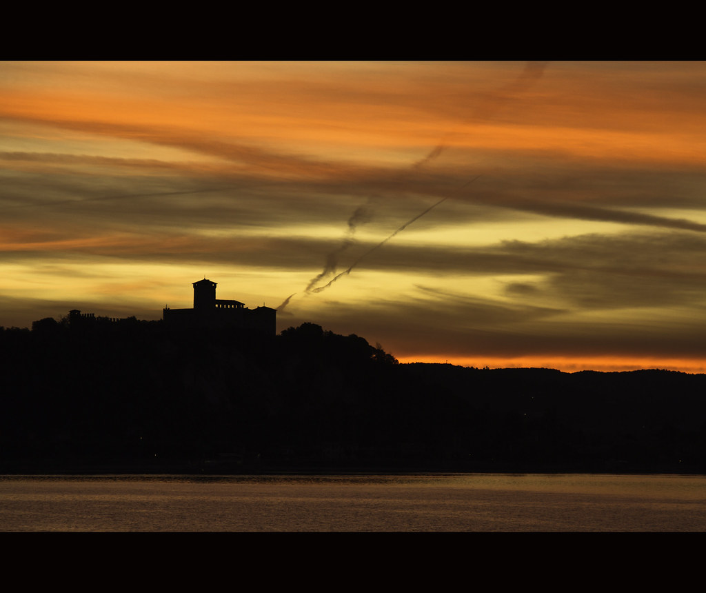 Hilltop fortress silhouette at Lago Maggiore sunset, Italy
