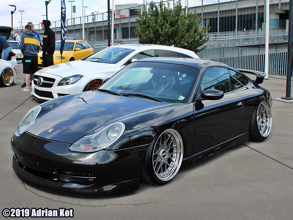 Black Porsche 911 (996) at a car show: three-quarter view, low stance, and polished multi-piece wheels