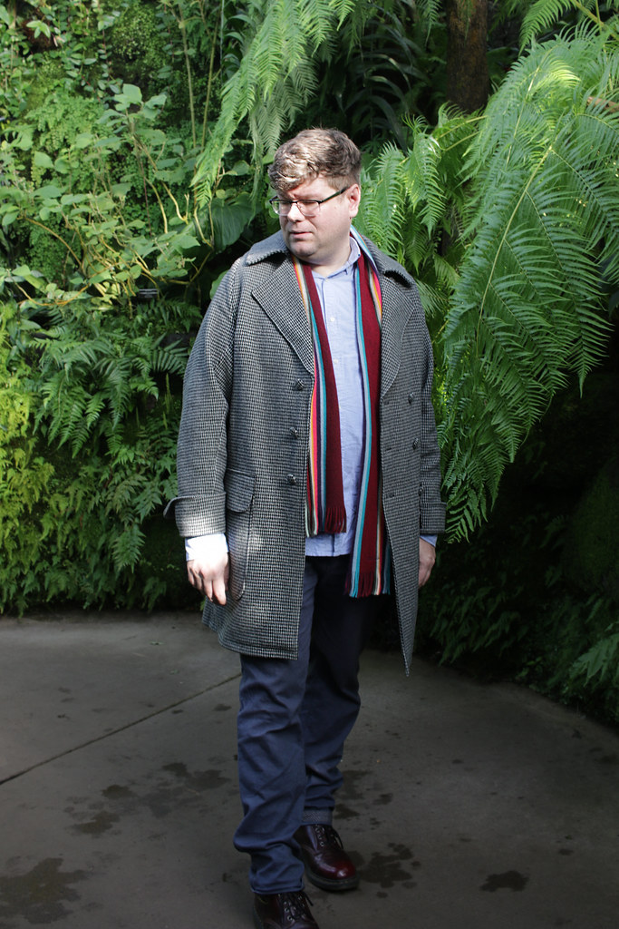 FreeSewing Carlton Coat in a lush garden: man wearing a houndstooth overcoat and striped scarf