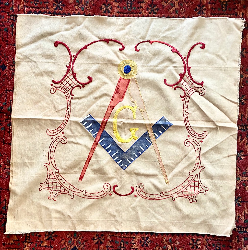 Embroidered Masonic Square and Compasses motif on ivory pillowcase with ornate red border