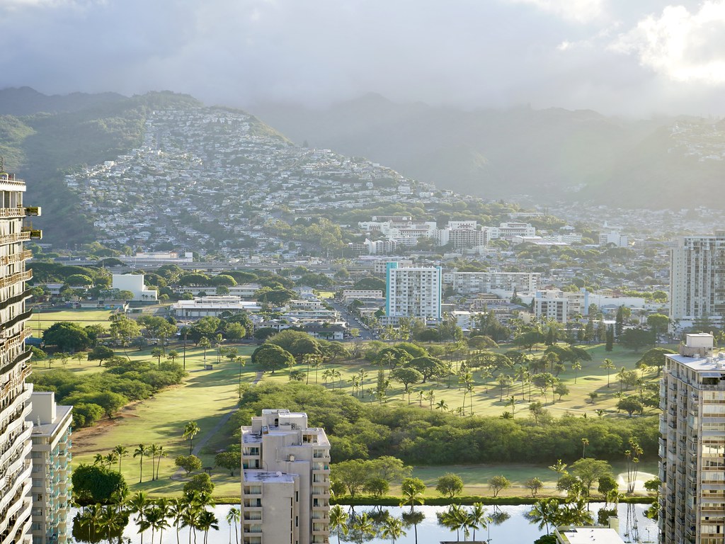 Honolulu Skyline from a High-Rise View: Golf Course Greens, Palm Trees, and Mountain Backdrop at Morning Light