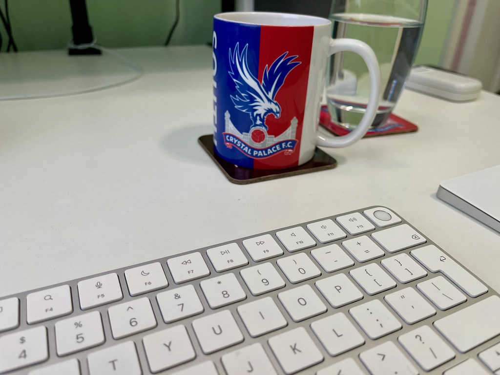 Tea at the desk: Crystal Palace mug beside a clean keyboard setup