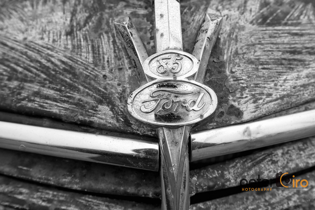 1955 Ford V8 Emblem: Close-Up of Weathered Chrome on a Classic Ford Hood
