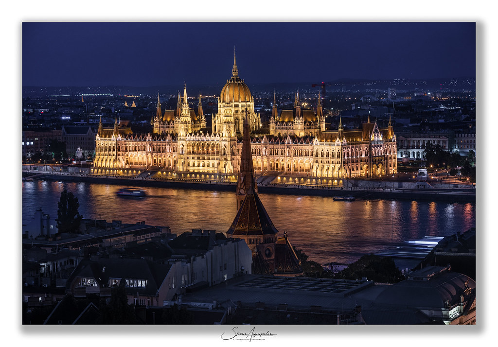 Budapest's Hungarian Parliament Building at night along the Danube with a glowing Neo-Gothic façade