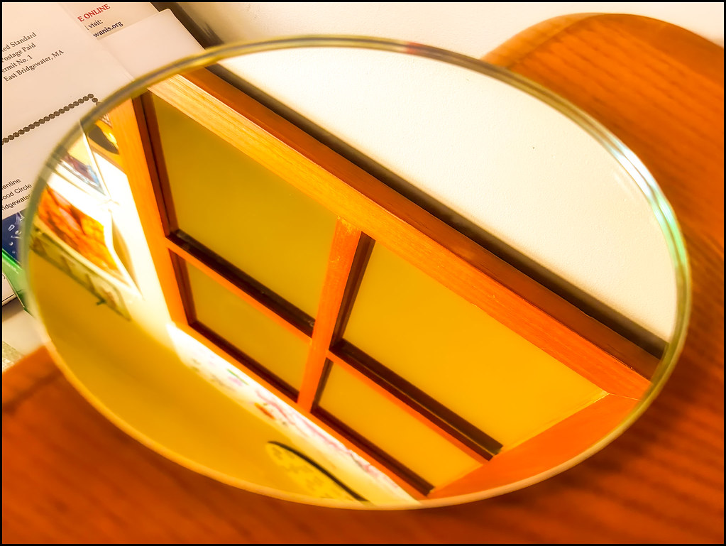 Tilted Circular Mirror Reflecting Amber Ceiling Beams in an Abstract Interior Study