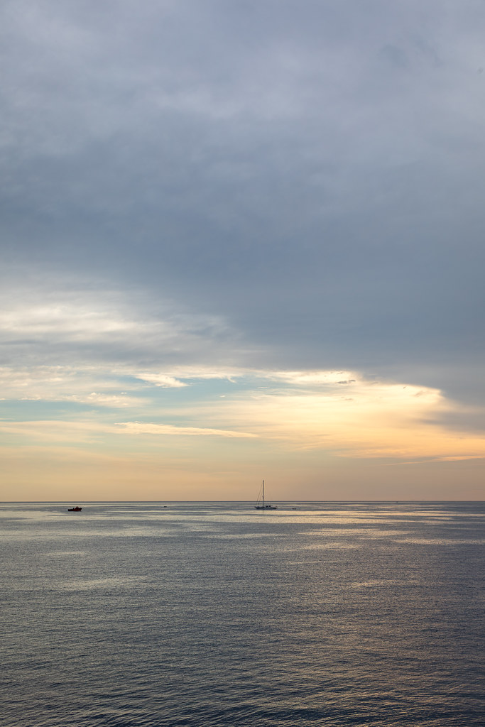 Sicilian Sea Sunset: Sailboat and Distant Vessel across a Calm Mediterranean Horizon