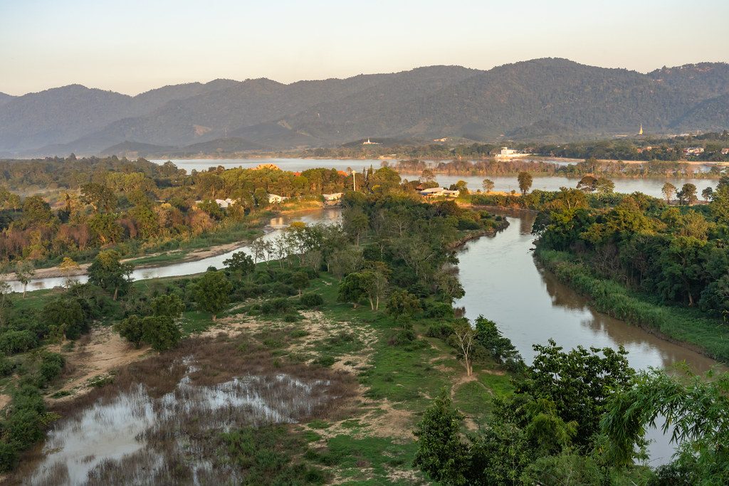 Aerial View over Thailand's Golden Triangle: Meandering River through Lush Hill Country at Golden Hour