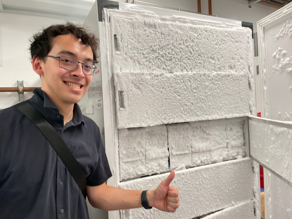 Portrait of a smiling man with glasses beside frost-coated insulated panels in a cold-storage facility