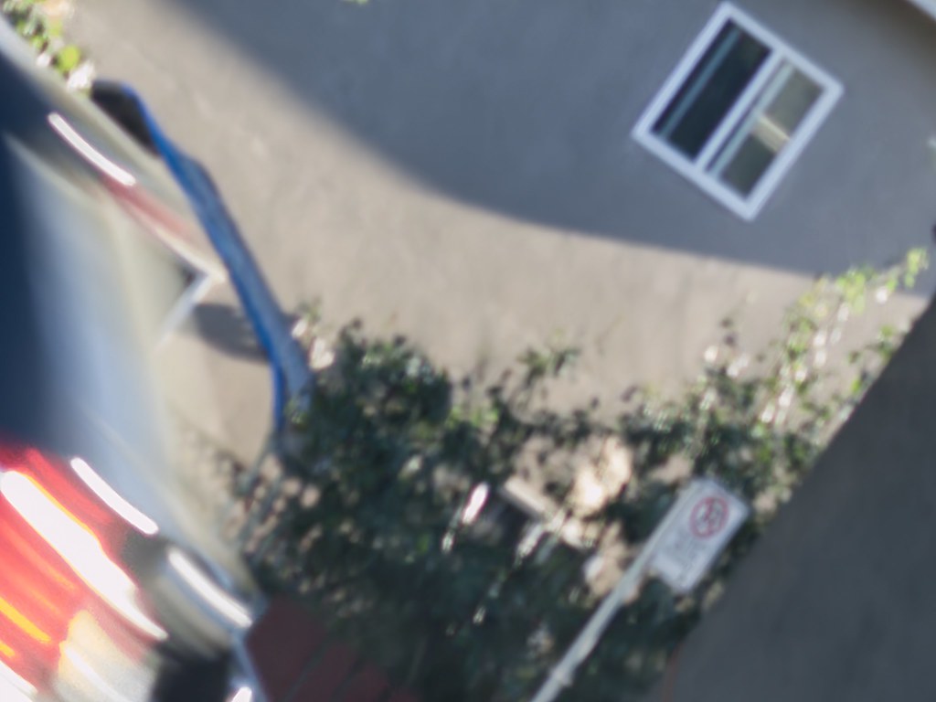 East Vancouver Tilt: Blurred taillights beside a gray stucco wall with greenery, July 15, 2025