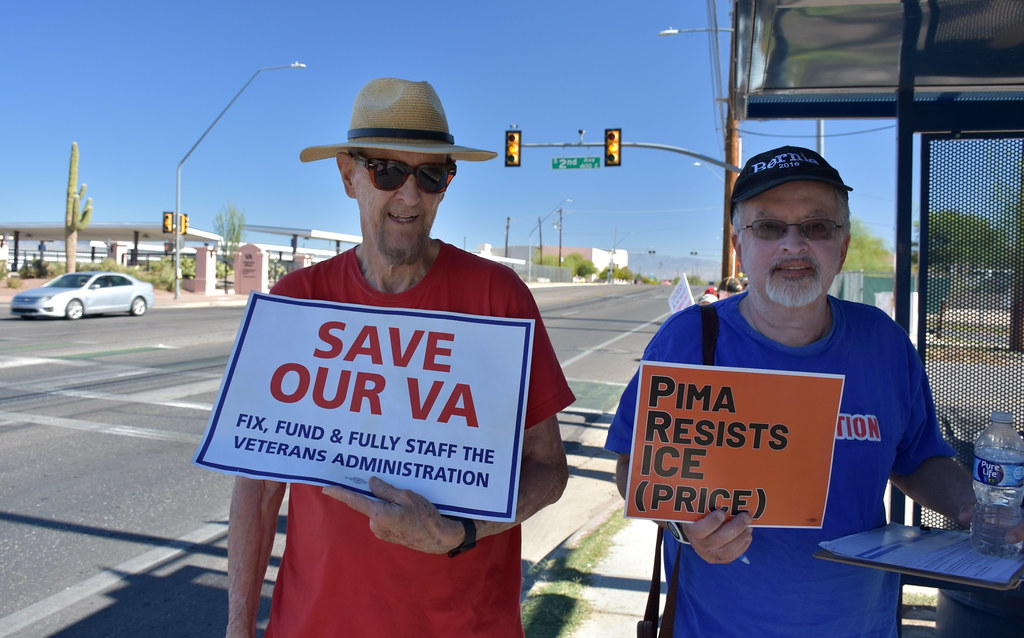 Protesters hold SAVE OUR VA and PIMA RESISTS ICE (PRICE) signs at a Tucson street corner