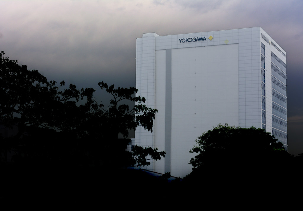 Yokogawa Office Tower, Bedok South, Singapore — silhouetted trees frame a white high-rise at dusk
