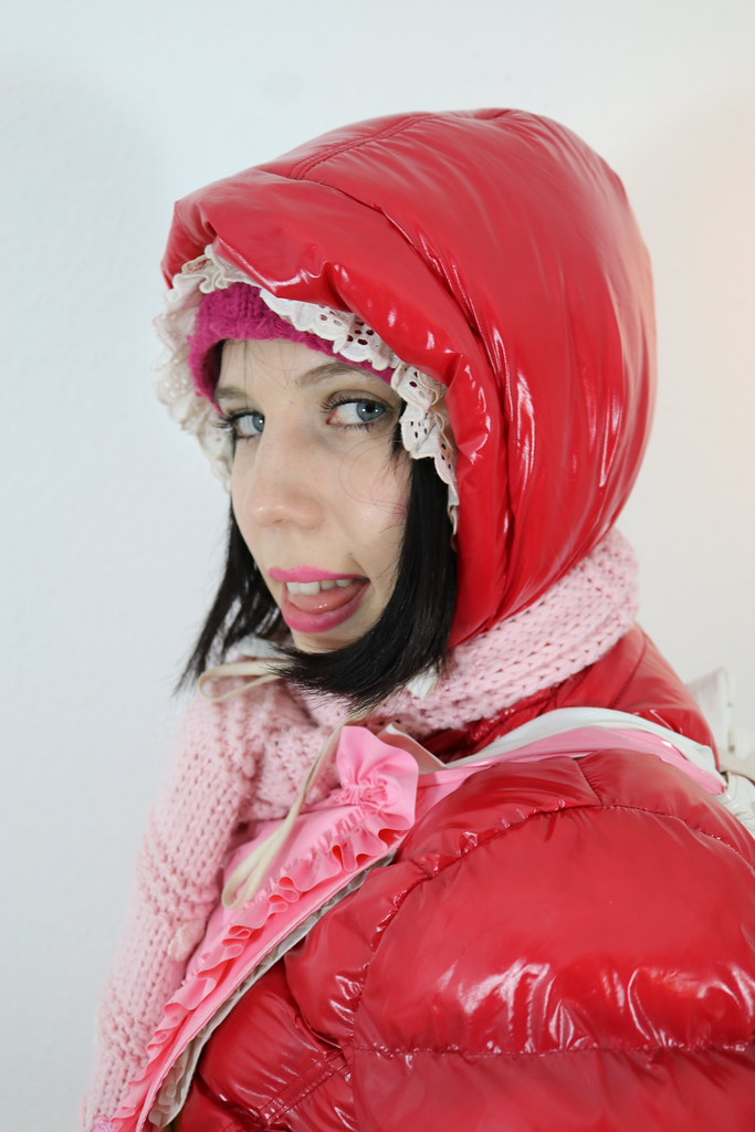 Portrait of a woman in a glossy red hooded puffer jacket with pink scarf and lace trim