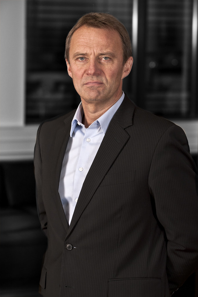 Portrait of a business professional in a charcoal pinstripe suit, standing in an indoor office setting