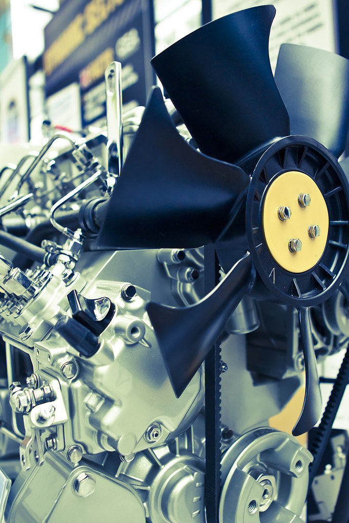 Close-up of an industrial engine: cooling fan with yellow hub and belt-drive components