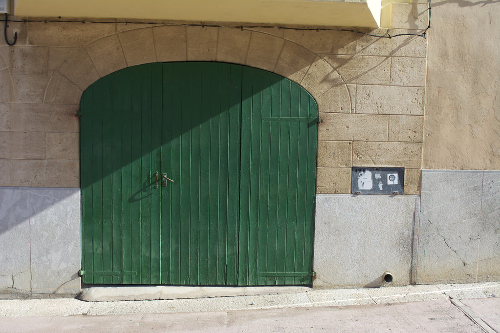 Emerald Green Arched Door Set in Weathered Stone Wall