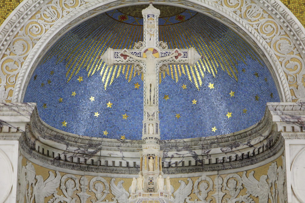 Crucifix centerpiece framed by a celestial blue mosaic dome in a marble chapel arch