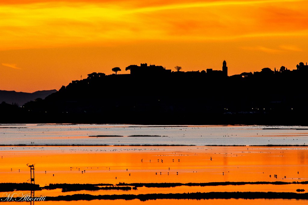 Diaccia Botrona at Golden Hour: Silhouetted town and marsh beneath a fiery sunset