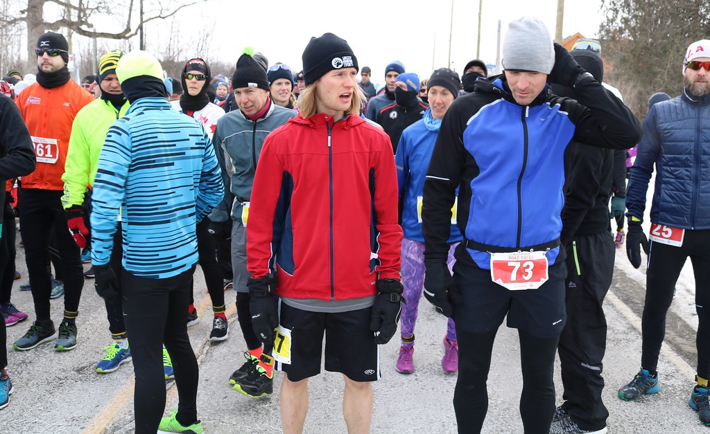 Winter Road Race Start: Diverse Runners in Neon Jackets Line Up on a Gray Street