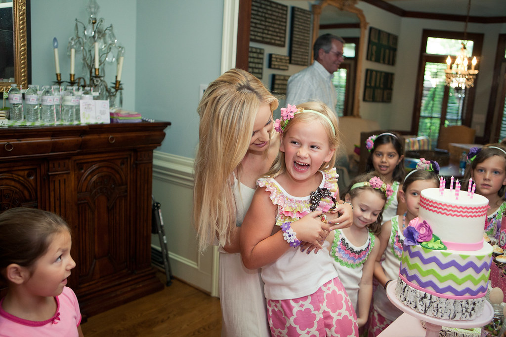 Joyful Birthday Moment: A young girl savors her celebration as friends gather around a pastel chevron cake