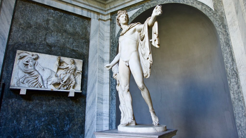 Marble Nude under Archway: Classical statue in a museum alcove beside a bas-relief panel