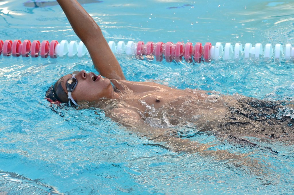 Freestyle swimmer breathing mid-stroke in a blue competition pool with lane dividers