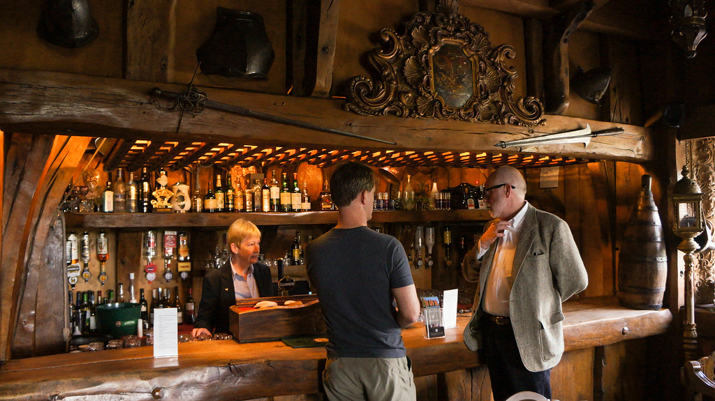 Belleek Castle Bar: warm timber interior with a carved oak counter and patrons conversing at the bar