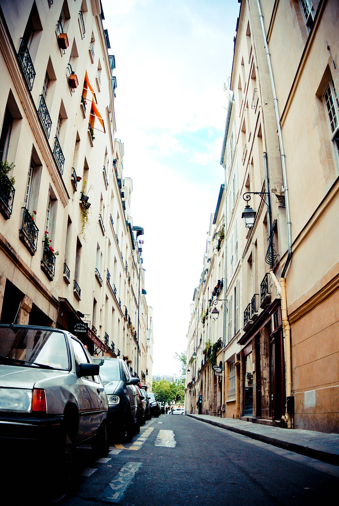 Parisian Haussmannian Street Canyon: Narrow, car-lined Rue Framed by Tall Facades and Wrought-Iron Balconies
