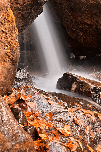 Autumn leaves cover wet rocks as a silky waterfall flows through a narrow rock crevice in Patapsco Valley State Park's Orange Grove area near Baltimore.