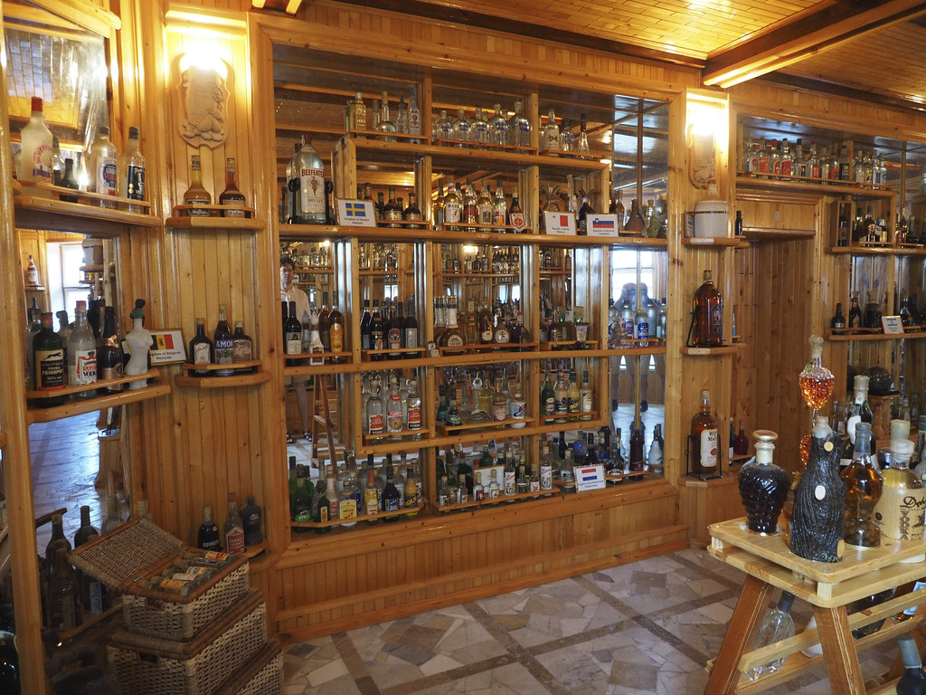 Interior of the Bottle Museum Hotel in Tîrnauca: Warm wood walls and shelves brimming with liquor bottles