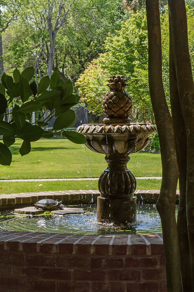 Pineapple-Finial Stone Fountain in a Brick-Edged Circular Basin, Framed by Trees in a Sunlit Park Garden